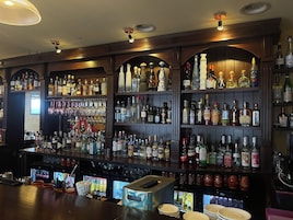 Um balcão de bar com prateleiras cheias de garrafas de bebidas e copos.