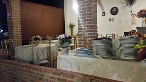Uma área de refeições com mesas postas, uma parede de tijolos e uma placa com a inscrição "Café".