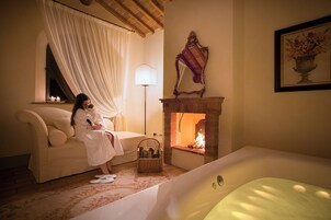 Um quarto aconchegante com lareira, sofá e banheira.