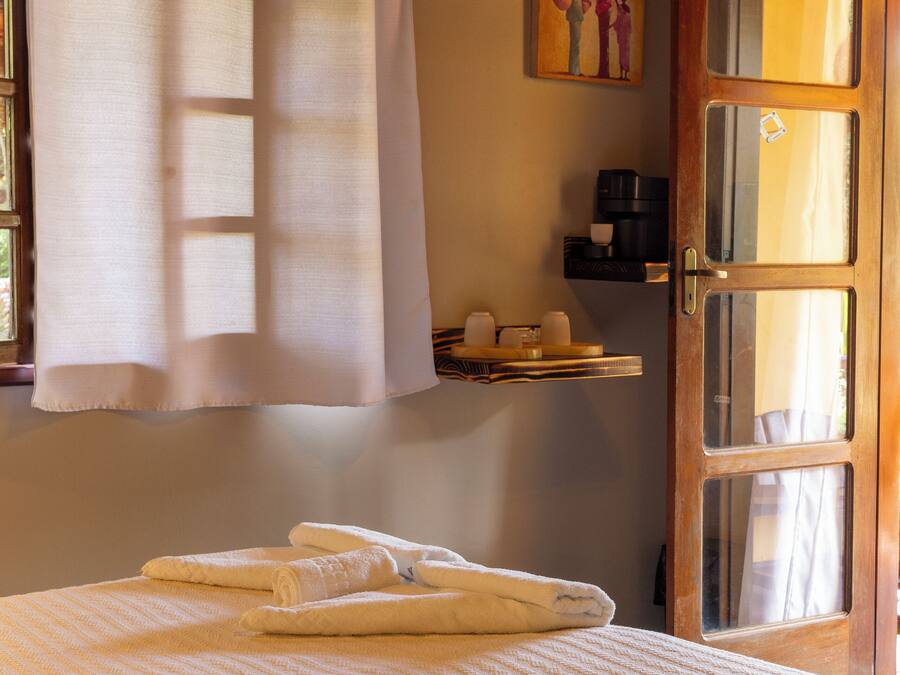 Quarto de hotel com cama, janela com cortinas, um quadro na parede e porta com espelho.
