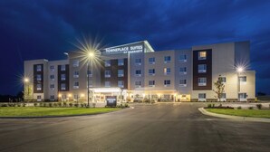 Um hotel moderno com uma placa que diz "TOWNEPLACE SUITES BY MARRIOTT" e uma entrada bem iluminada.