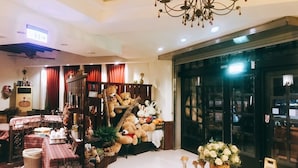 Um saguão de hotel acolhedor com uma exposição de animais de pelúcia, um lustre e um balcão de recepção.