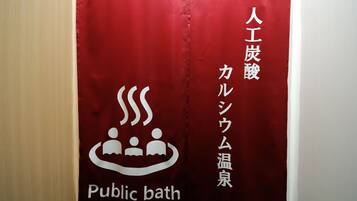 Tapete de banho vermelho com texto em japonês e um ícone de banho público.