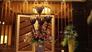 Um lobby com um grande lustre, um painel decorativo e um arranjo floral.