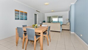 Sala moderna com área de jantar, sofá e uma grande janela com vista.
