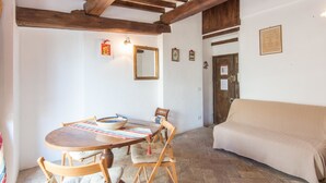 Uma sala de jantar com mesa de madeira, cadeiras e sofá bege.