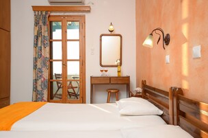 Quarto de hotel com cama, escrivaninha de madeira, espelho e luminária.
