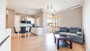 Uma sala de estar moderna com um sofá cinzento, uma mesa de centro e um espaço de refeições com cadeiras e uma mesa.