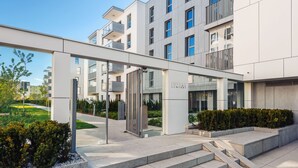 Um edifício moderno com entrada de vidro, área de estar externa e um jardim bem cuidado.