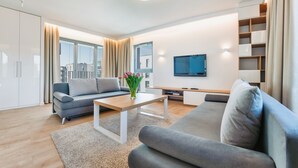 Uma sala de estar moderna com um sofá, uma mesa de centro e uma televisão.