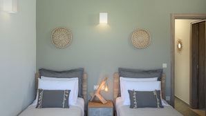 Quarto com duas camas, teto de madeira e ar-condicionado fixado na parede.