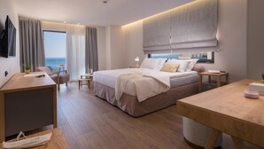 Quarto de hotel moderno com uma cama grande, uma escrivaninha e vista para o mar.