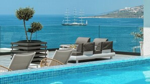 Área da piscina com espreguiçadeiras e vista para o mar.