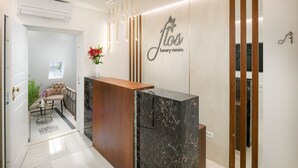 Uma área de recepção com um balcão de mármore, uma divisória de madeira e uma placa com a inscrição "flos luxury rooms".