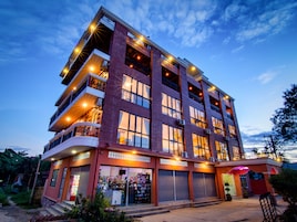 Um hotel com vários andares, varandas, janelas grandes e um espaço comercial na base.