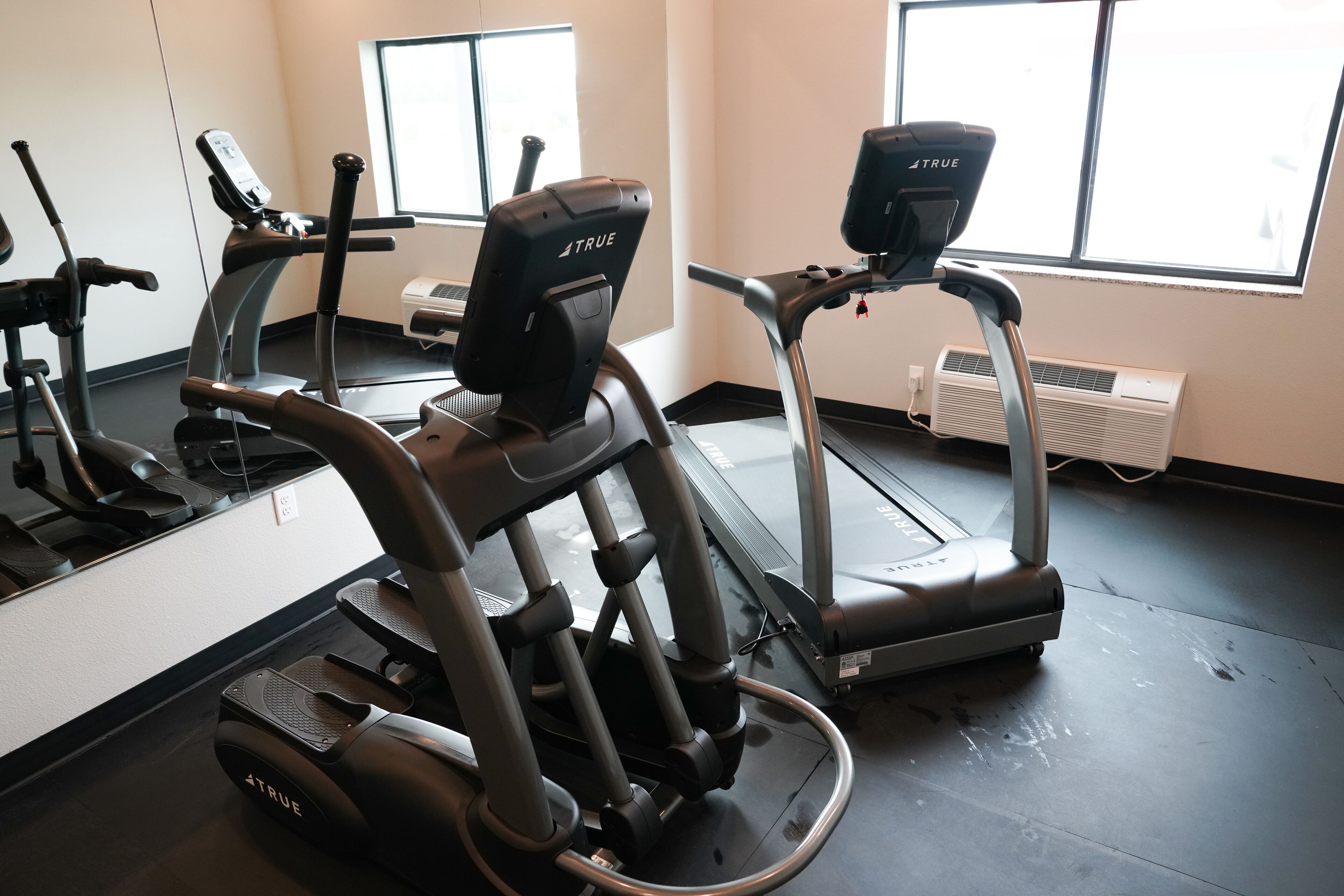 Uma academia com diversos equipamentos de exercício, incluindo esteiras e elípticos.