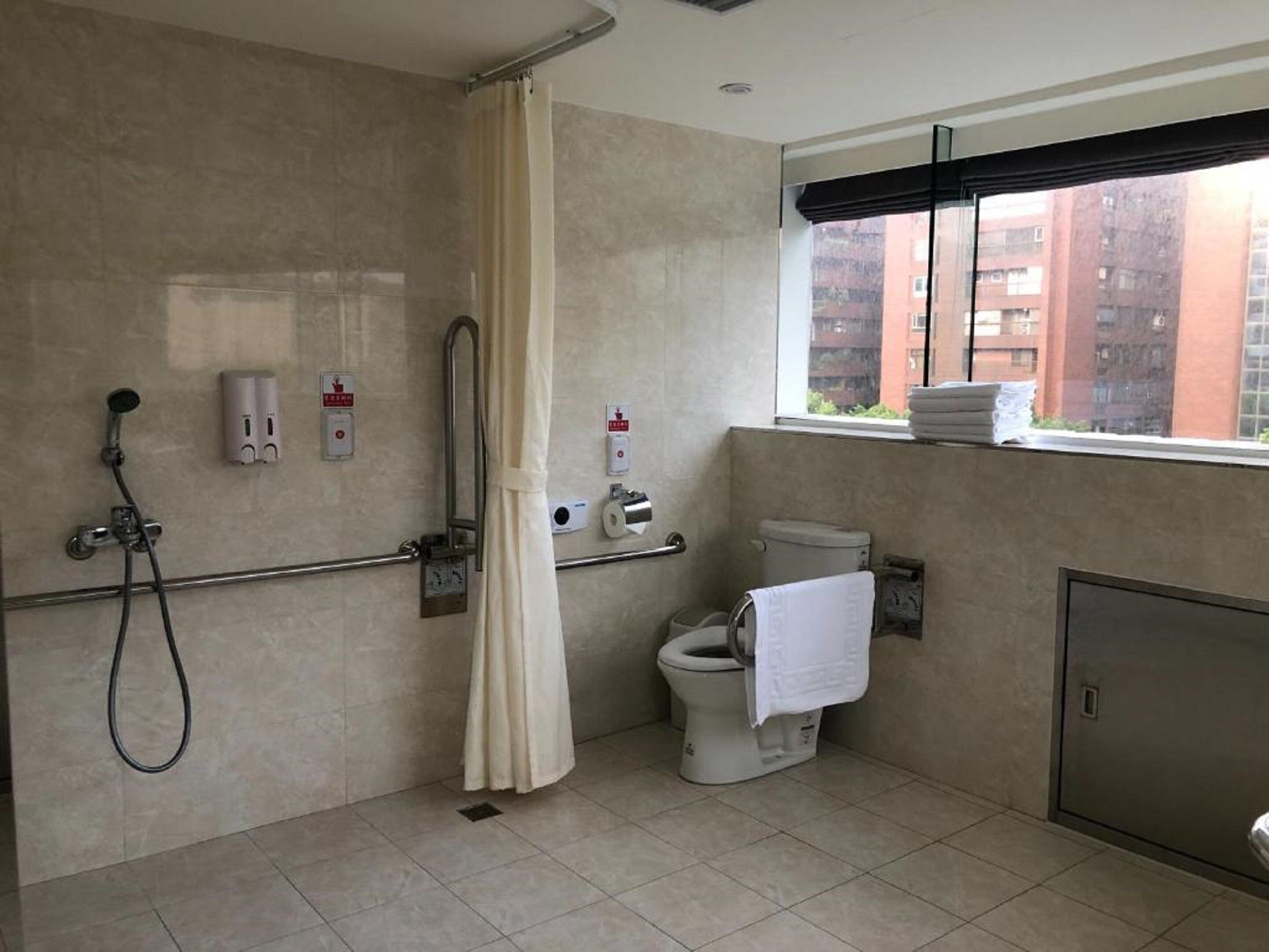 Casa de banho com chuveiro, sanita e dispensadores de gel desinfetante.