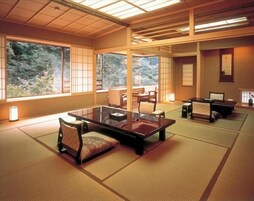 Um quarto japonês tradicional com piso de tatame, uma mesa baixa e cadeiras.