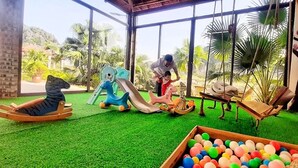 Uma área de recreação com escorrega, cavalinhos de balanço e piscina de bolinhas.