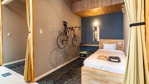 Quarto de hotel com uma cama, uma bicicleta, uma mesa de cabeceira e um espelho.