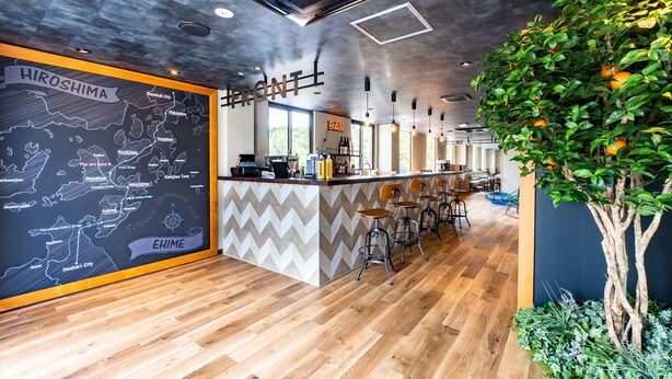 Uma área de bar moderna com um mapa de Hiroshima, banquetas e uma árvore decorativa.