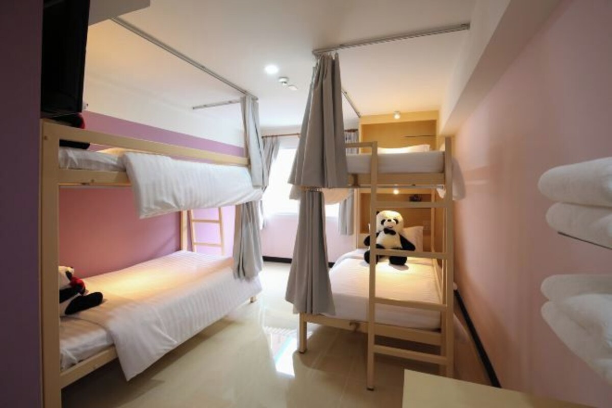 Quarto com beliche, mesa de estudo e um urso de pelúcia panda.