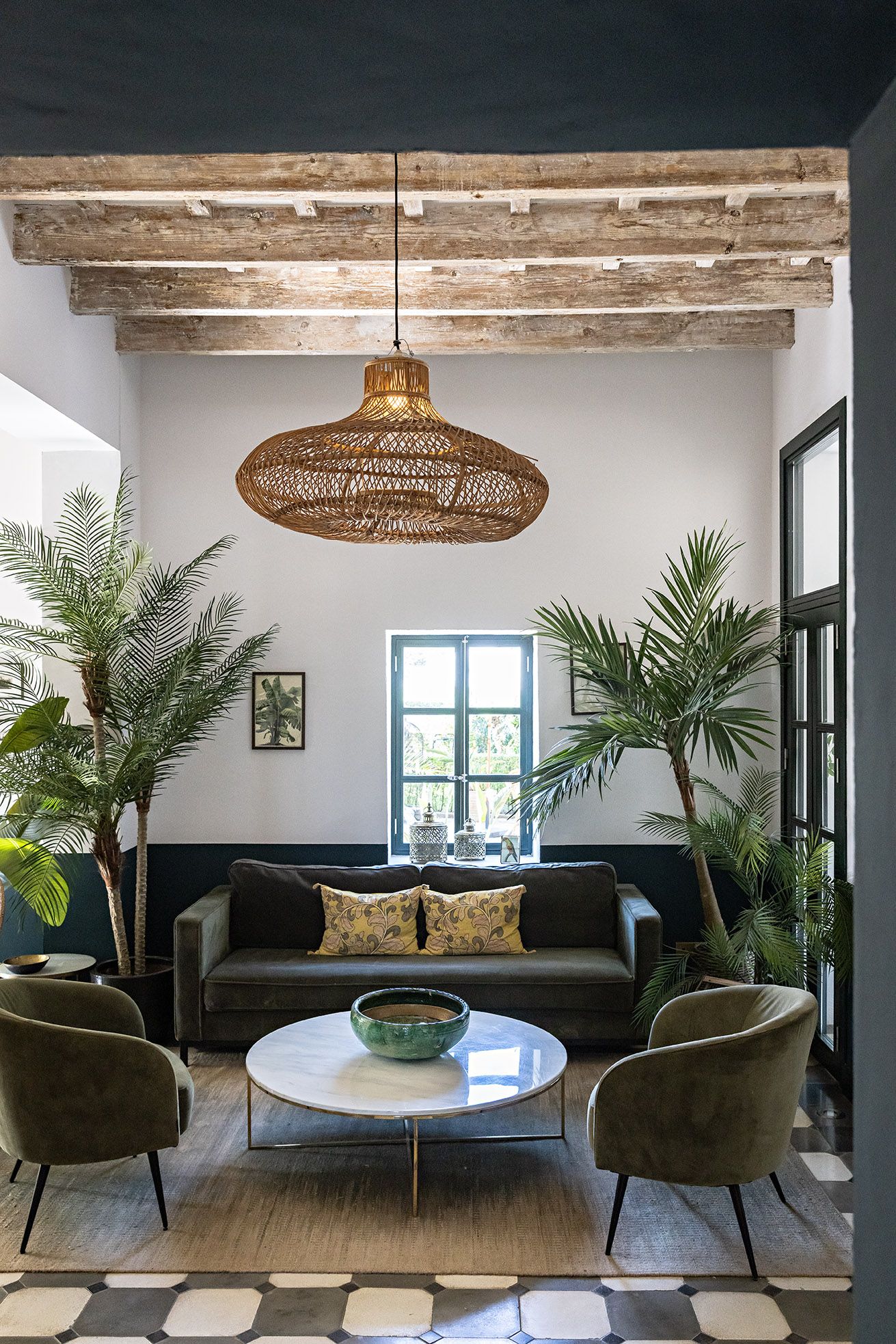 Uma sala de estar moderna com sofá, duas poltronas, mesa de centro e um grande luminário trançado.