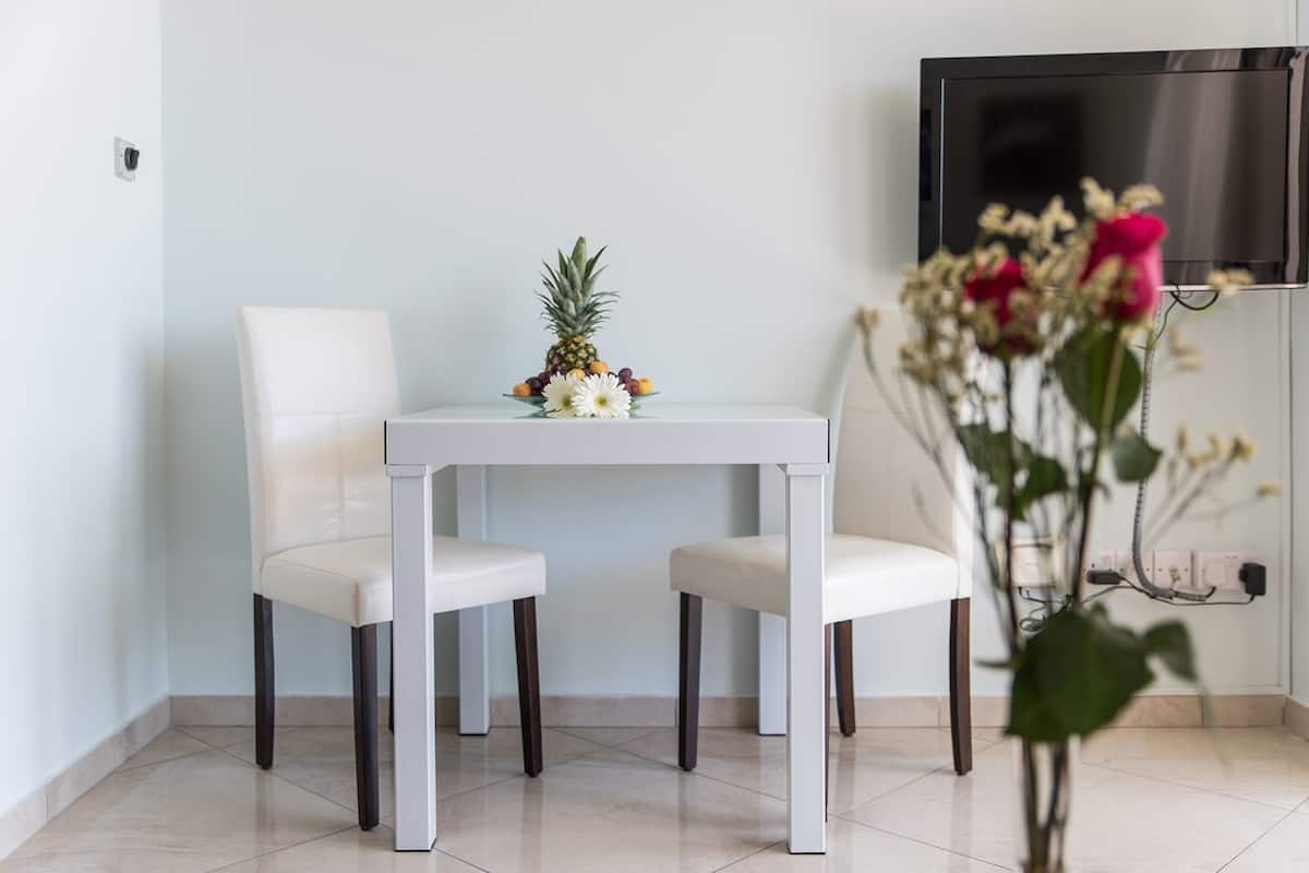 Uma mesa pequena e branca com duas cadeiras, uma abacaxi e um arranjo de flores.