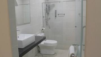 Uma casa de banho moderna com cabine de duche em vidro, uma sanita branca e uma pia.