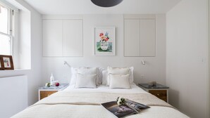Quarto com cama, mesa de cabeceira e um quadro pendurado na parede.