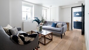 Uma sala de estar moderna com um sofá cinzento, uma mesa de centro e um vaso com flores.