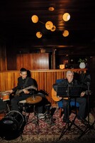 Um quarto com painéis de madeira, um tapete estampado e um grupo de músicos com instrumentos.