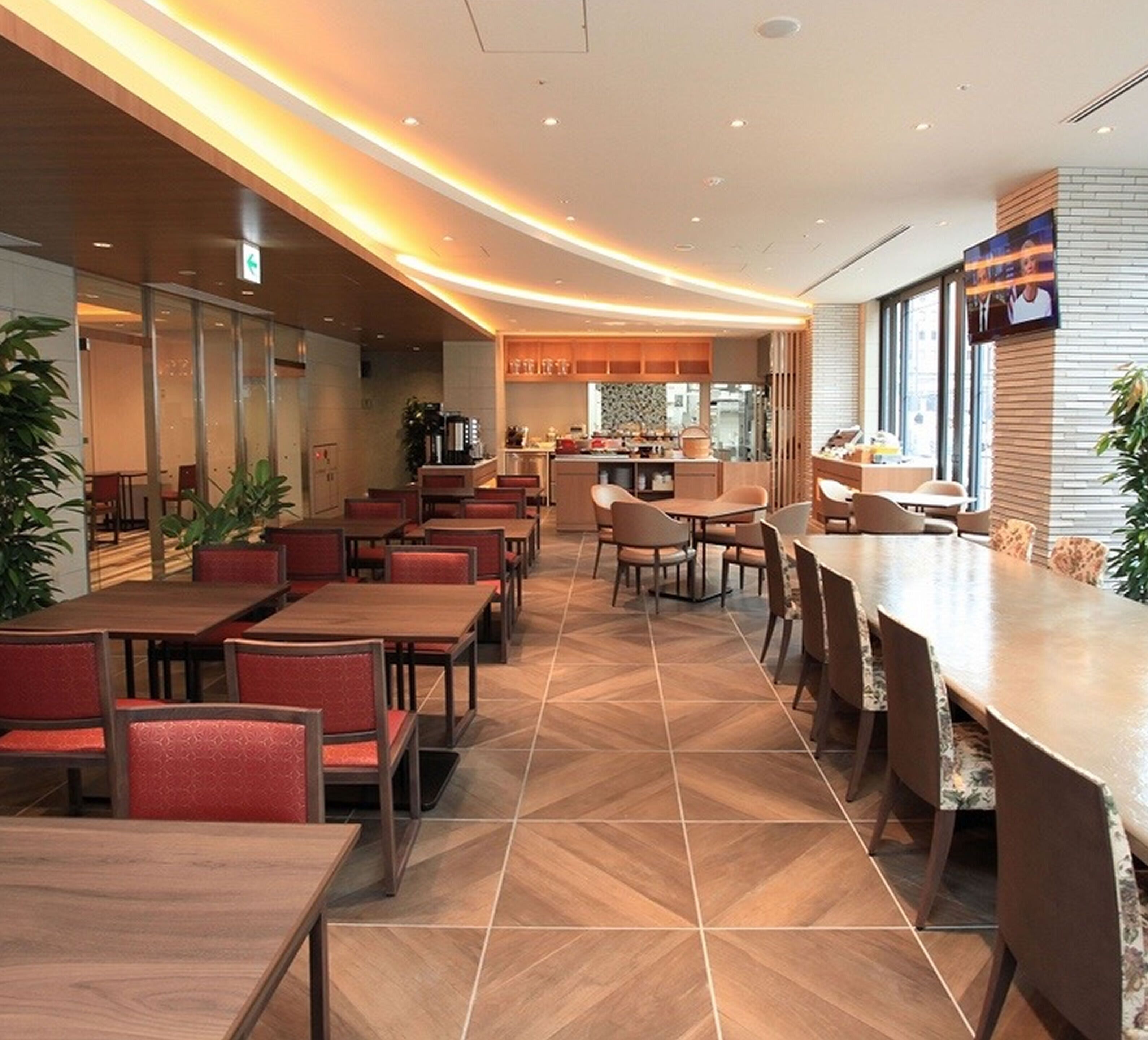 Um restaurante moderno com um balcão extenso, várias mesas e cadeiras. Uma área de cozinha é visível ao fundo.
