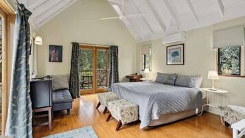 Quarto com cama, sofá, mesinha, cadeira e janela com cortinas.