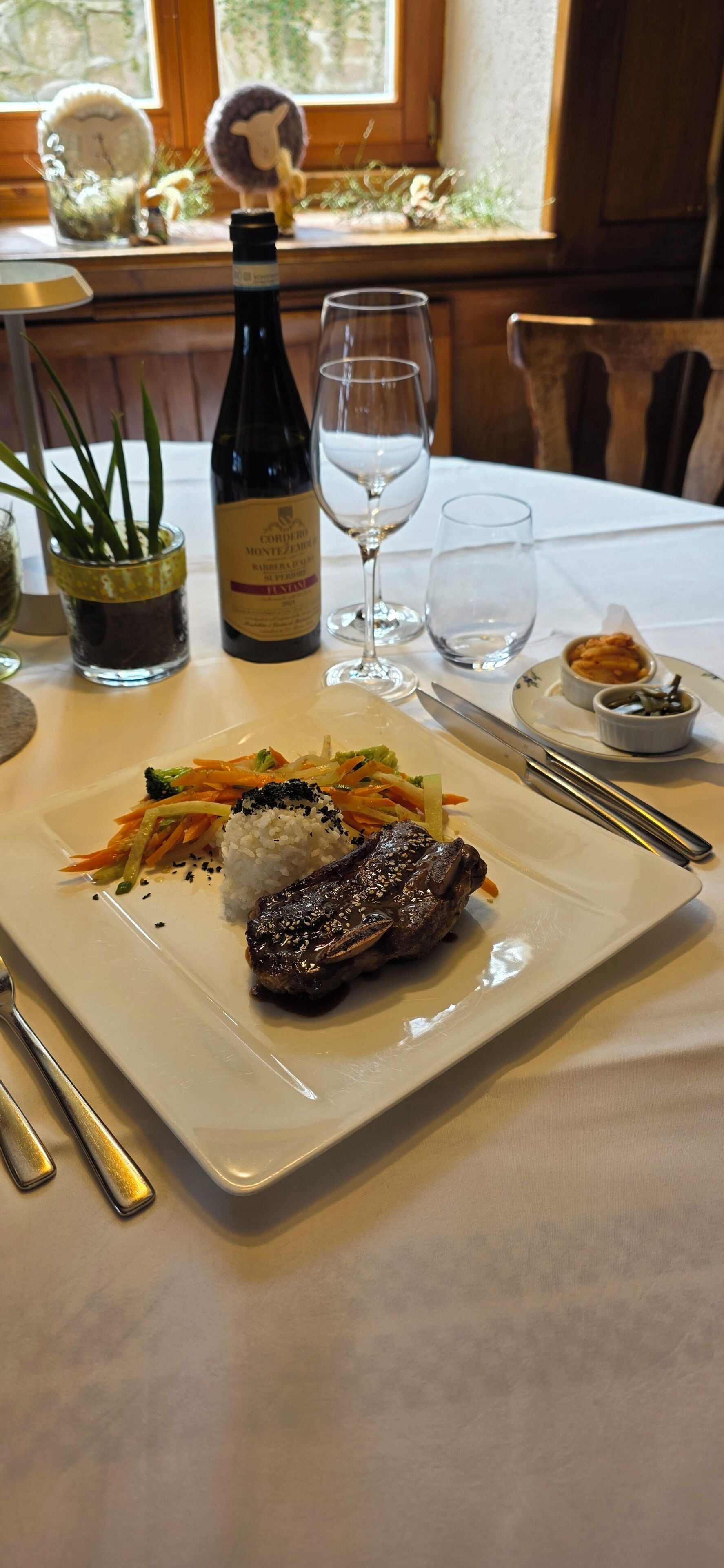 Uma mesa de jantar com um prato de comida, uma garrafa de vinho e um copo.