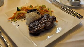 Uma mesa de jantar com um prato de comida, uma garrafa de vinho e um copo.