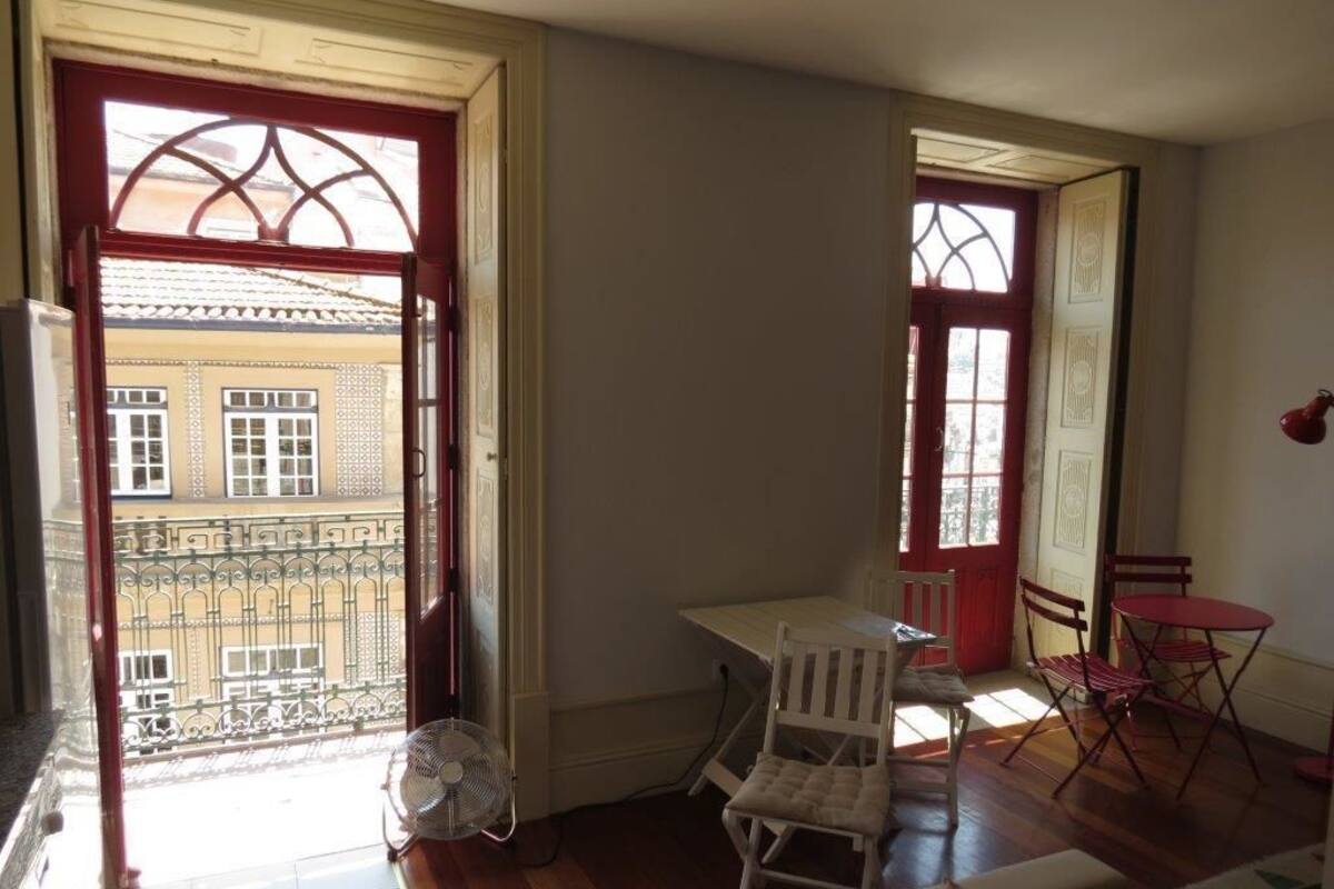 Quarto com varanda, ventoinha, mesa e duas cadeiras.