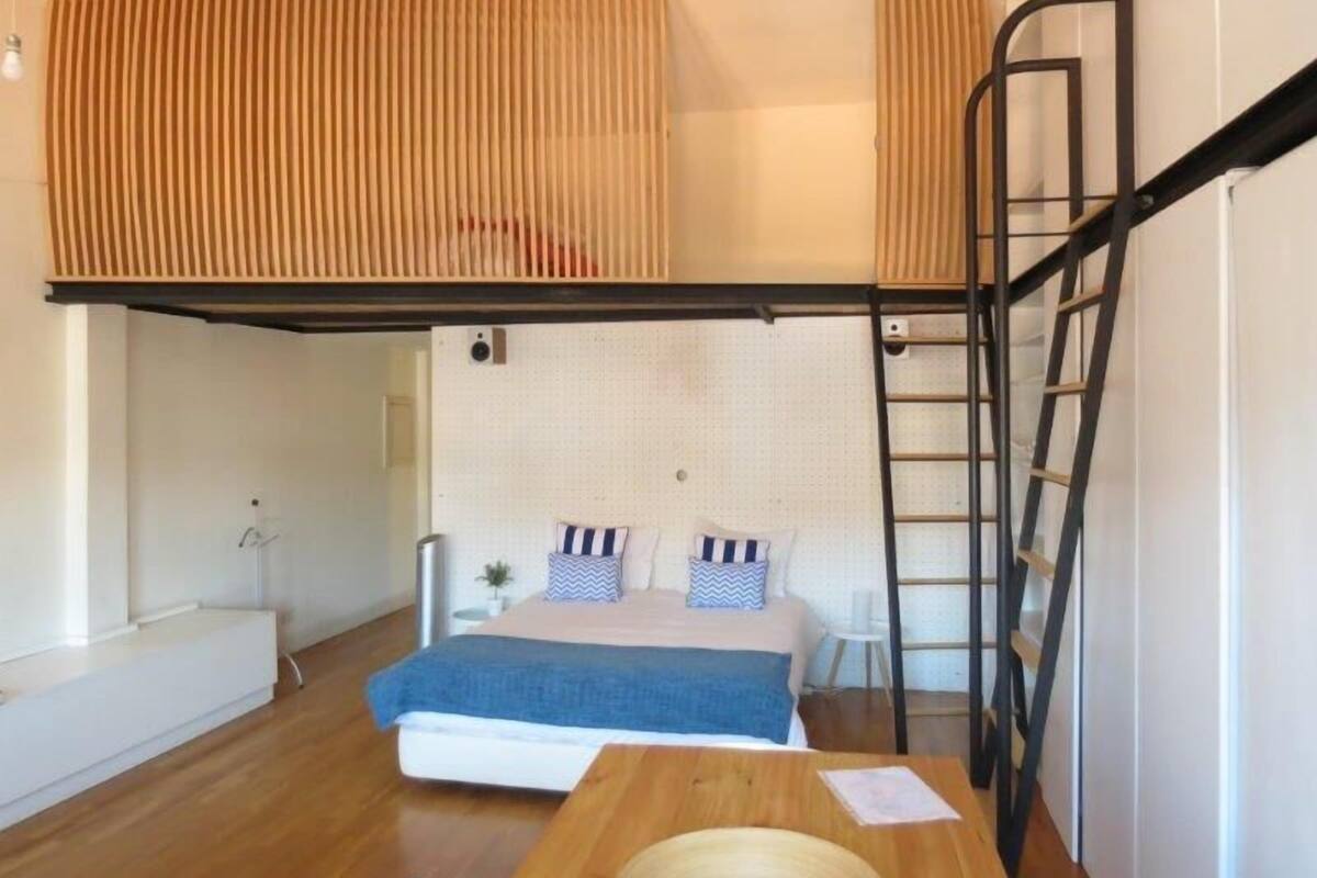 Quarto pequeno com beliche, uma mesinha e escada.