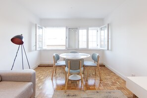 Uma sala de jantar moderna com uma mesa redonda, quatro cadeiras e um abajur.