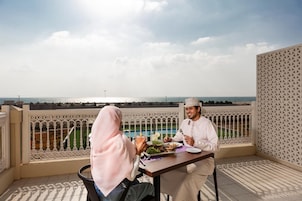 Duas pessoas jantando em uma varanda com vista para a piscina.