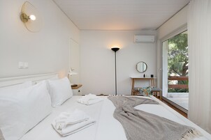 Quarto de hotel com cama, mesa de cabeceira, luminária, espelho e vista para o exterior.