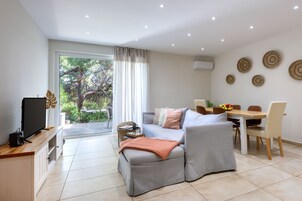 Uma sala de estar moderna com sofá, TV e área de jantar.