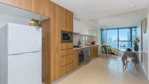 Cozinha moderna com armários de madeira, micro-ondas embutido e área de refeições com vista para a cidade.