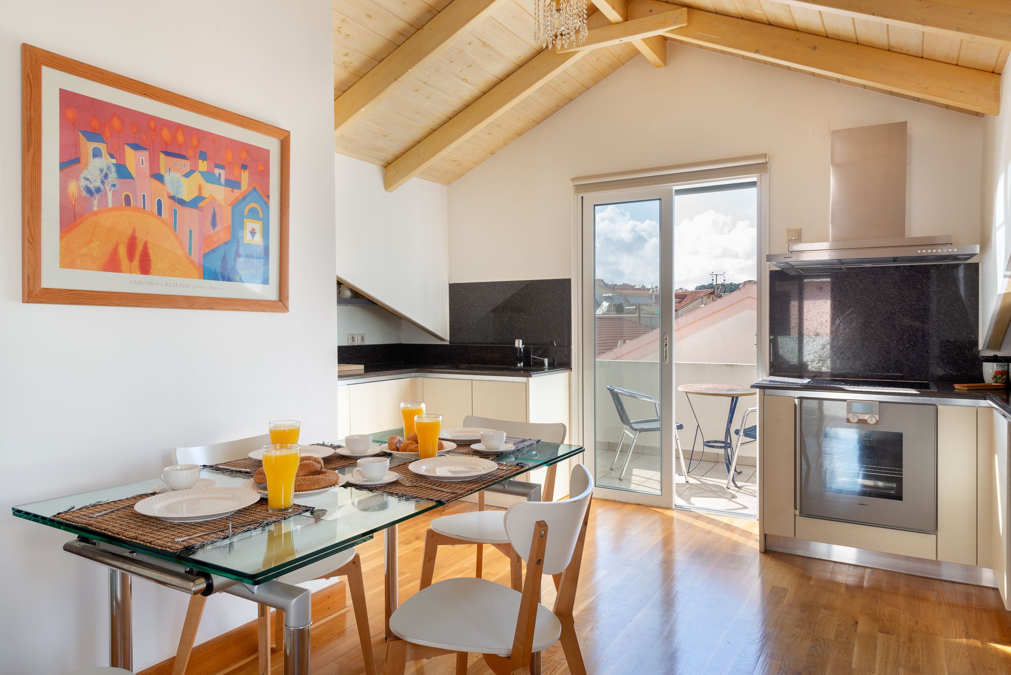 Cozinha moderna com mesa de vidro, cadeiras e preparação para o café da manhã.