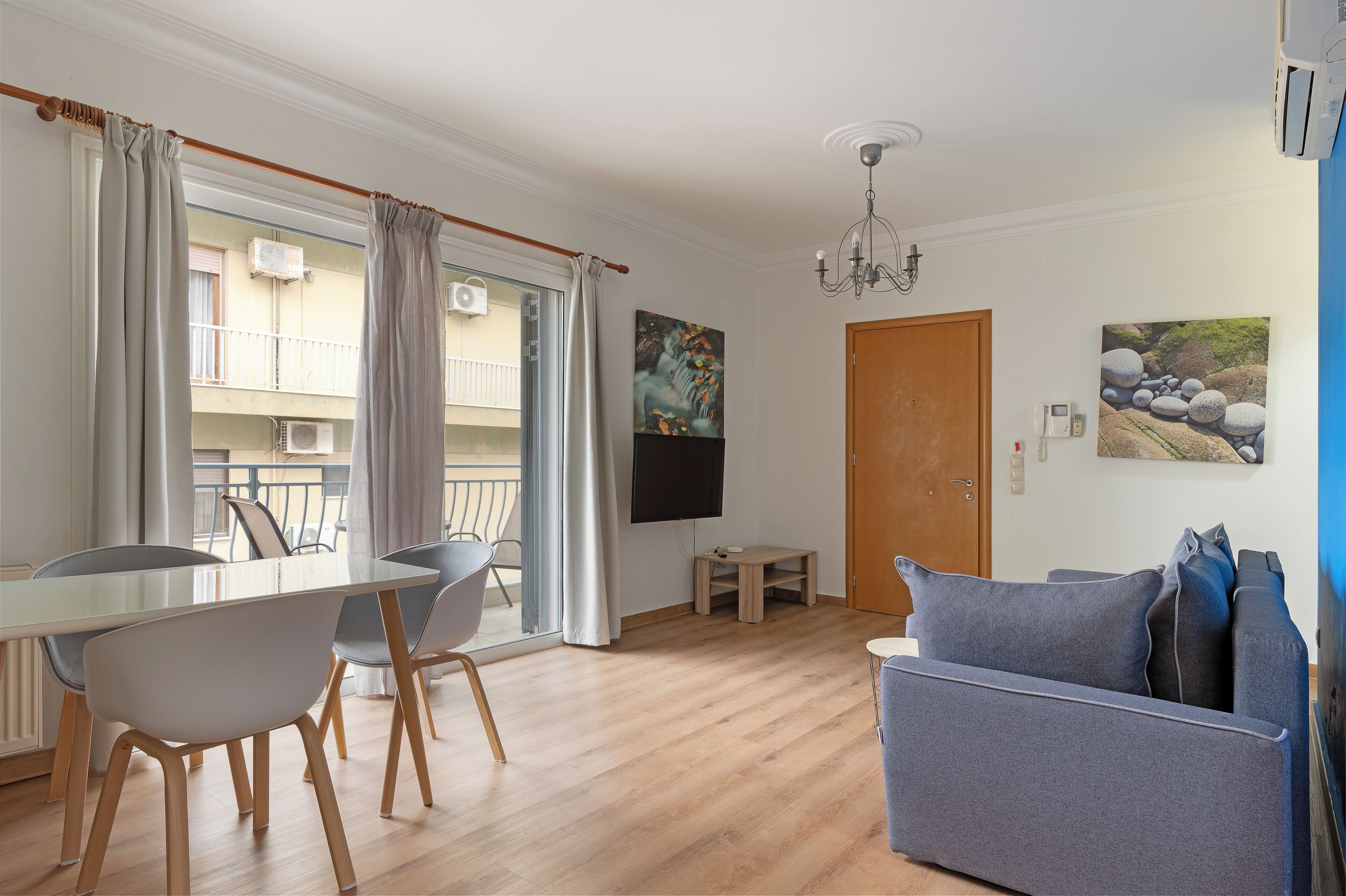 Uma sala de estar moderna com área de jantar, sofá, televisão e varanda com vista.