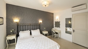 Quarto com cama grande, mesas de cabeceira, cadeira, escrivaninha e guarda-roupa.