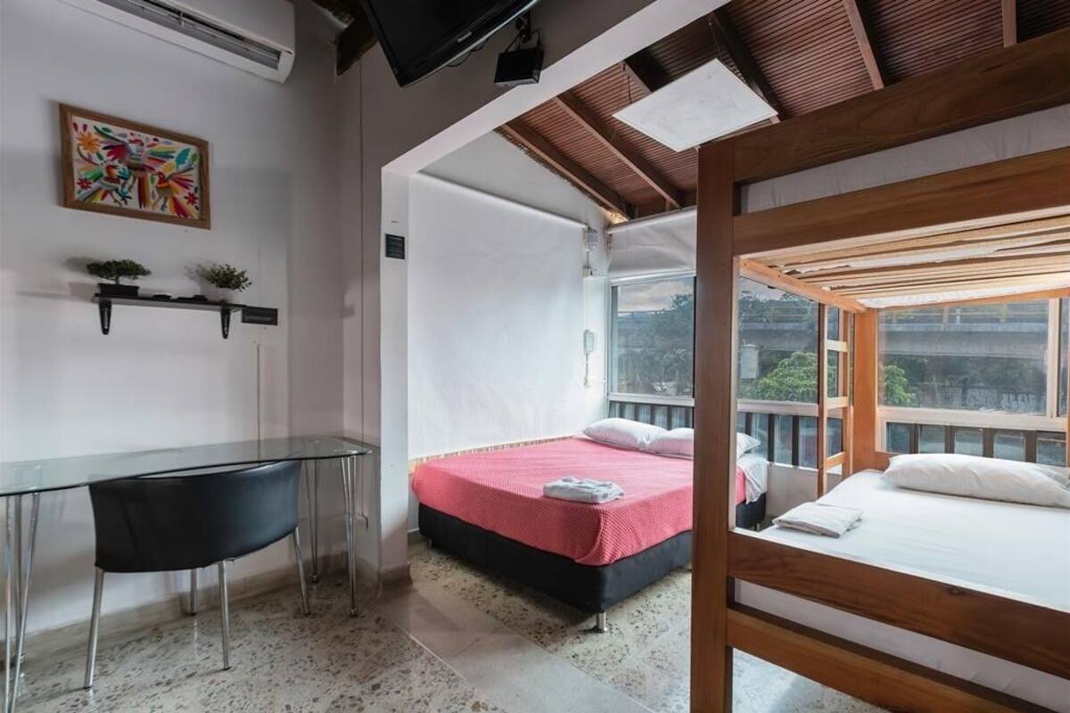Quarto com uma cama, uma escrivaninha e uma janela.