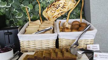 Buffet com cestas de pão, pães e uma fatia de bolo de cenoura.