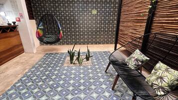 Um interior moderno com piso estampado, cadeiras de metal preto, uma cadeira suspensa e uma parede de bambu.