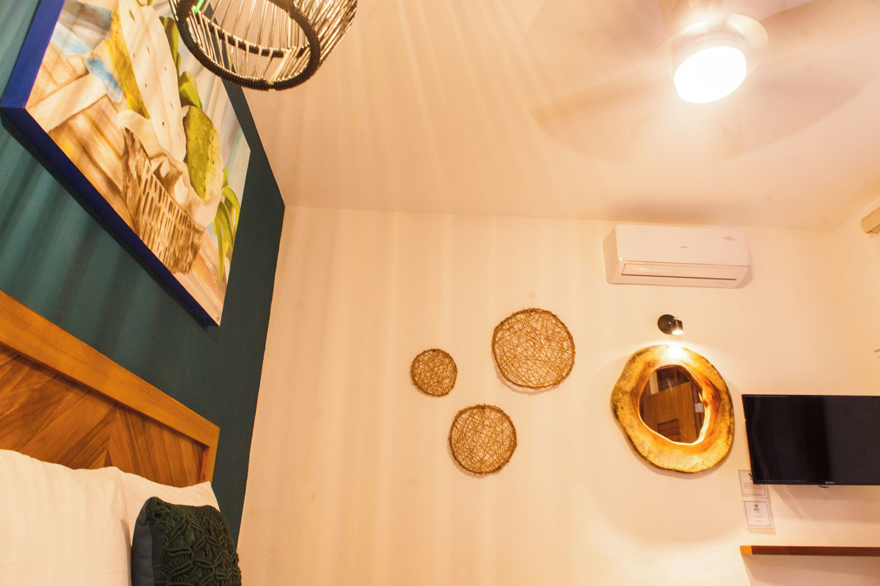 Quarto com cama, ar-condicionado fixado na parede e objetos decorativos feitos de fibra.